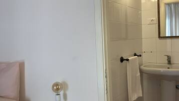 Uma casa de banho com lavatório, espelho e porta-toalhas.