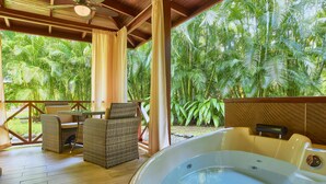 Área externa coberta com hidromassagem, móveis de vime e vegetação tropical exuberante.