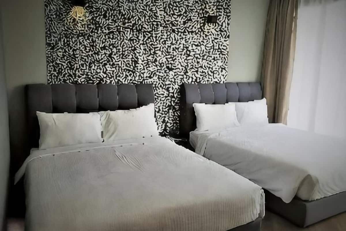 Duas camas com cabeceiras, parede estampada e janela com cortinas.