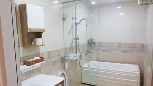 Um banheiro moderno com chuveiro em box de vidro, uma banheira independente e vaso sanitário.