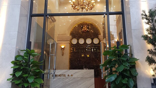 Entrada de hotel com um arco imponente, um candelabro e um balcão de recepção.