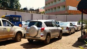 Um estacionamento com vários carros, incluindo um SUV prateado e uma carrinha azul.