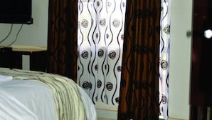 Quarto com uma cama, escrivaninha e cortinas estampadas com flores.