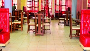 Restaurante com assentos estofados em vermelho e mesas de madeira.