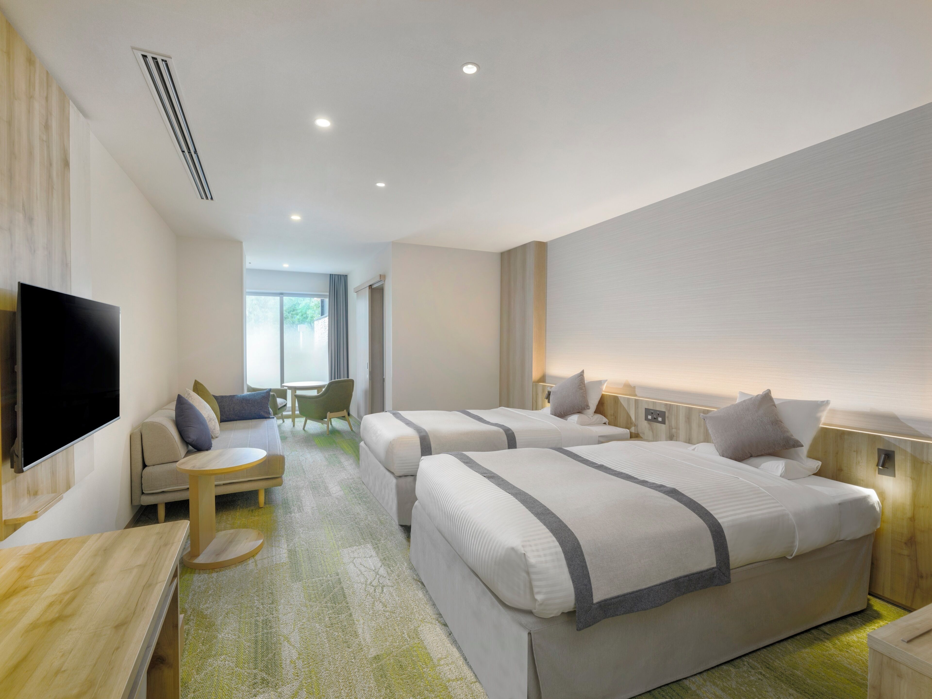 Quarto de hotel com duas camas, televisão, mesa pequena e uma cadeira.