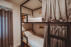Quarto com beliche, prateleira e ar condicionado.