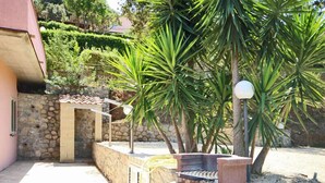 Um muro de pedra, uma churrasqueira e um poste de luz em uma área de jardim.