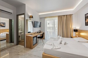 Quarto de hotel com uma cama grande, uma escrivaninha com computador, televisão e área de chuveiro.