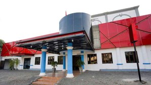 Um edifício com telhado vermelho, colunas azuis e uma área de entrada coberta.