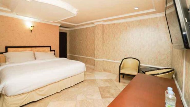 Quarto de hotel com cama, cadeira, mesa e televisão.