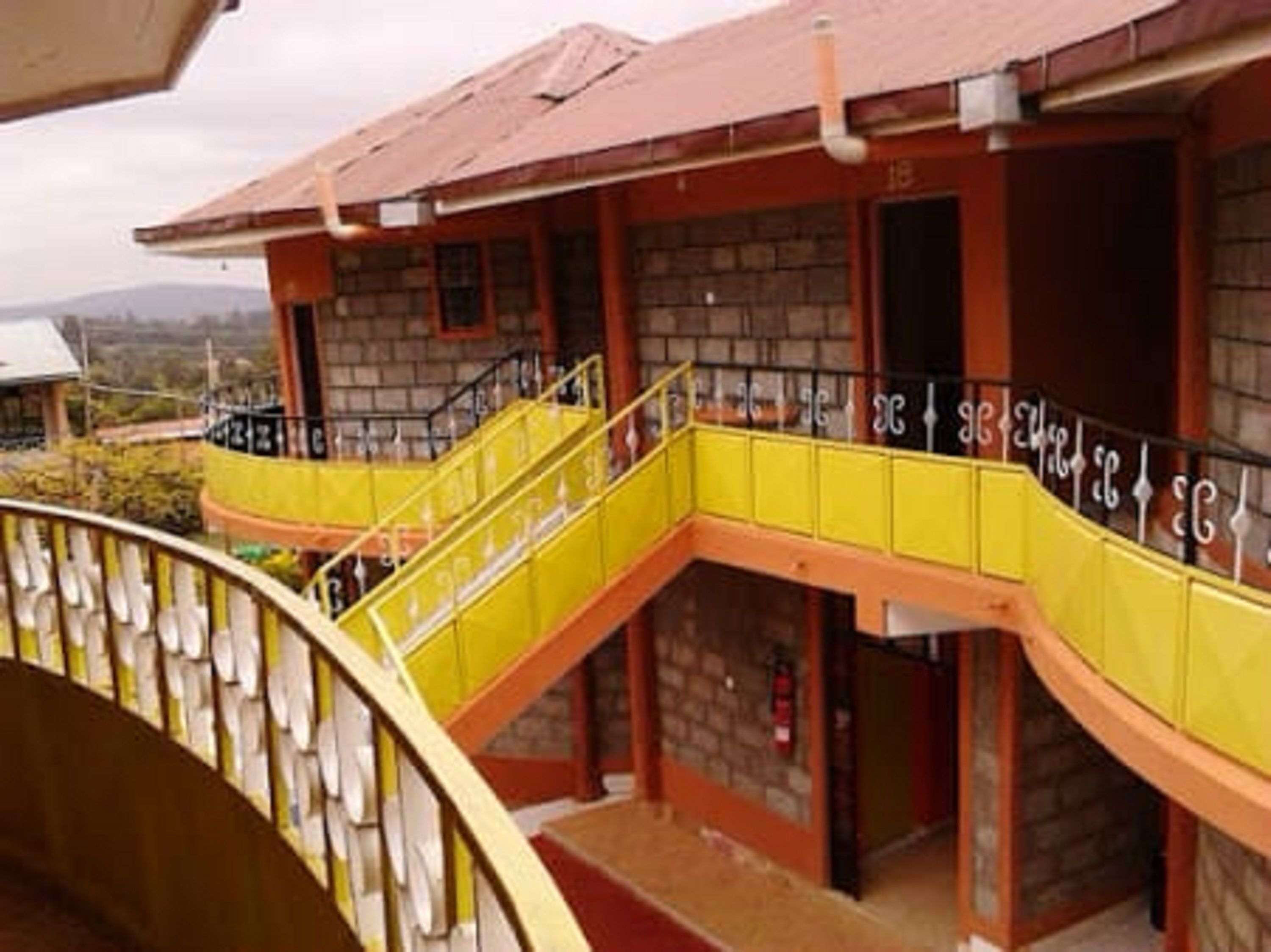 Um edifício com fachada de tijolos e exterior amarelo, apresentando uma escadaria com guarda-corpo amarelo.