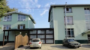Um edifício de dois andares com uma garagem e dois carros estacionados em frente.