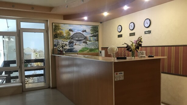 Bancada de recepção com um quadro, relógios e uma placa 'VISA'.