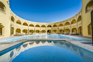 Uma área de piscina com vários níveis de arcos e uma piscina central.