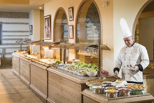 Disposição de buffet com diversos pratos e um chefe servindo comida.