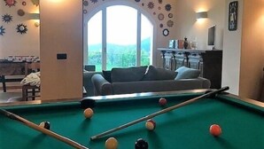 Uma mesa de bilhar com bolas, um sofá e uma sala de jantar com mesa e cadeiras.