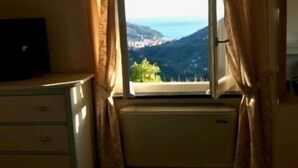 Um quarto com cama, penteadeira e janela com cortinas.