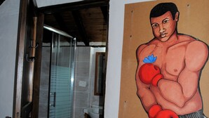 Quarto com um grande mural de um boxeador, teto de madeira e chão de azulejos.