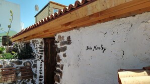 Um edifício rústico com parede de pedra, bancos de madeira e porta de madeira.