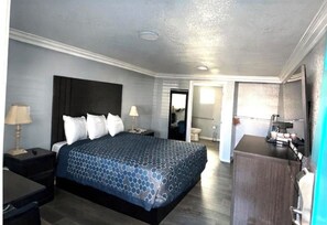 Quarto de hotel com uma cama grande, mesas de cabeceira, uma escrivaninha e um espelho.