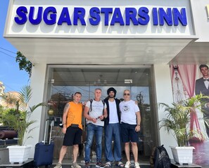 Um grupo de pessoas em frente a um hotel chamado 'Sugar Stars Inn'.