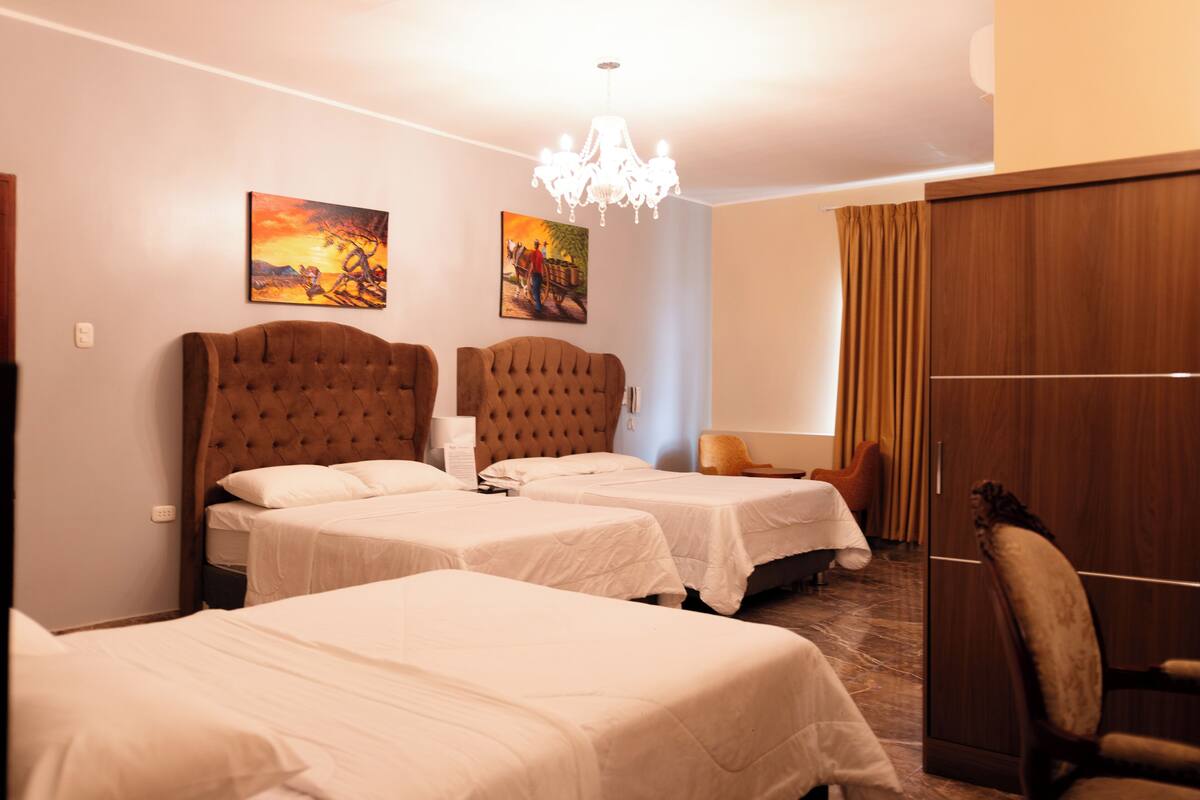 Quarto de hotel com duas camas, um candelabro e obras de arte nas paredes.