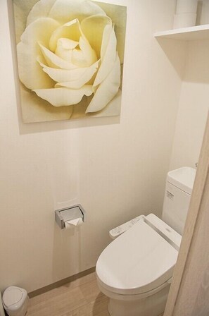 Uma casa de banho pequena com sanita, um caixote do lixo e um dispensador de toalhas de papel.