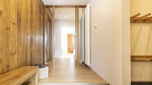 Um corredor com painéis de madeira em uma parede, um banco com cesta e piso de azulejos.