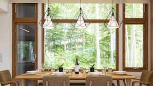 Uma sala de jantar com uma mesa de madeira posta para seis pessoas, rodeada por cadeiras.