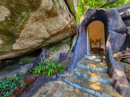 Escadaria de pedra que leva a um quarto com uma cama e uma parede decorada com objetos circulares.