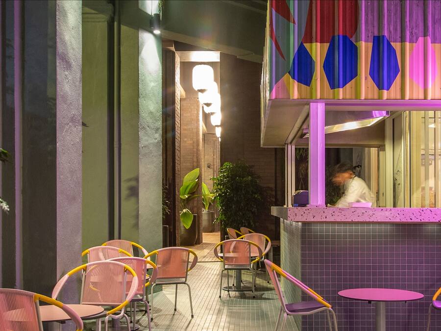 Um café com mesas ao ar livre, balcão e plantas em vasos.