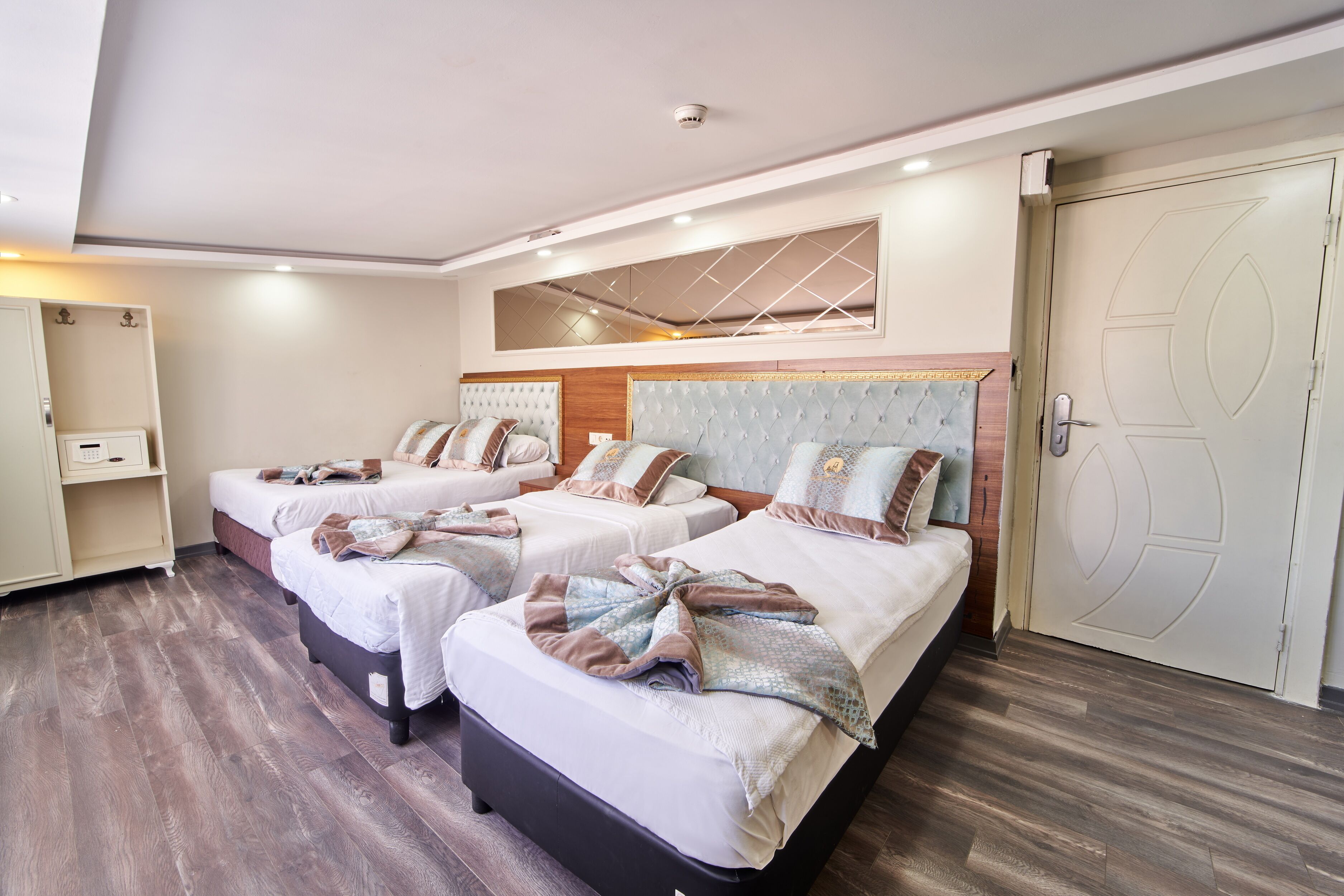 Quarto de hotel com duas camas, um guarda-roupa e um espelho grande.