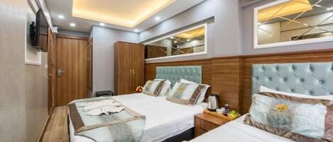 Quarto de hotel com duas camas, um espelho grande, ar condicionado e televisão na parede.