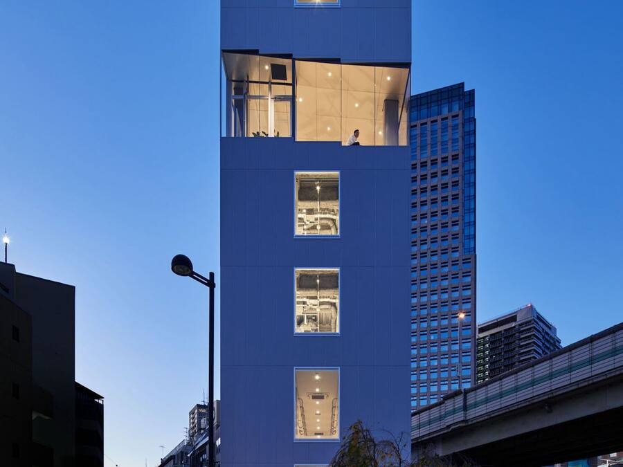 Um edifício moderno com um destaque para o letreiro '9h', várias janelas e uma entrada visível.