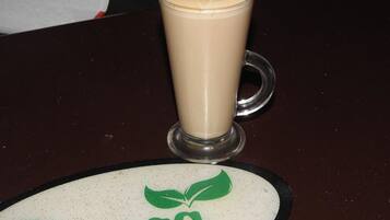 Um copo alto com uma bebida cremosa e arte de latte sobre uma superfície escura.