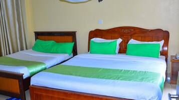 Quarto de hotel com duas camas de madeira, cada uma com roupa de cama verde e branca.