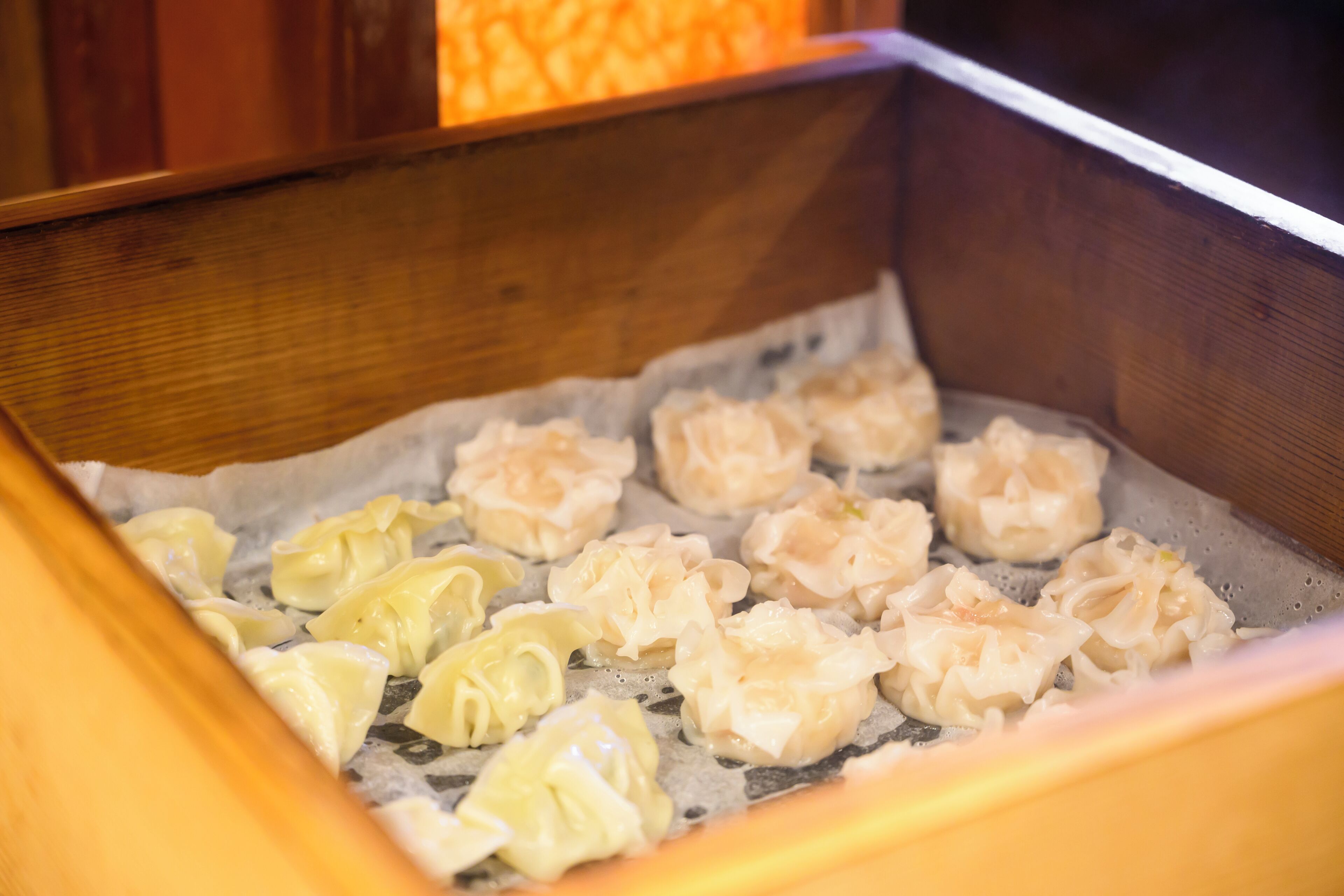 Uma travessa fumegante de dumplings em um recipiente de madeira.