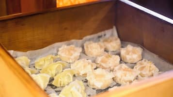 Uma travessa fumegante de dumplings em um recipiente de madeira.
