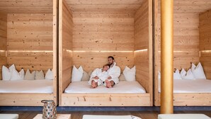 Um quarto estilo cabana de madeira com duas camas, cada uma com roupa de cama e almofadas brancas.