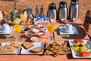 Mesa posta para o café da manhã, com torradas, ovos e frutas, acompanhados de condimentos e bebidas.