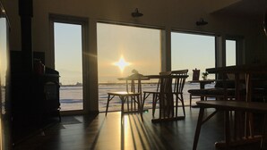 Um quarto com uma grande janela, uma mesa de madeira e cadeiras.