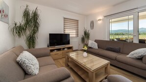 Uma sala de estar moderna com um conjunto de sofás, uma mesa de centro e uma televisão.
