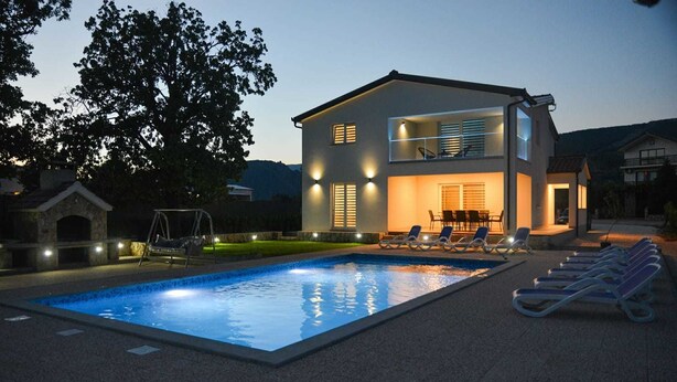 Uma casa moderna com piscina, espreguiçadeiras e um espaço de estar ao ar livre.