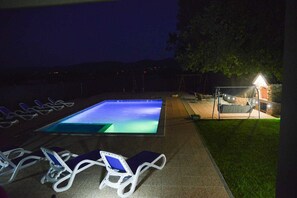 Piscina ao ar livre com espreguiçadeiras e área de hidromassagem.