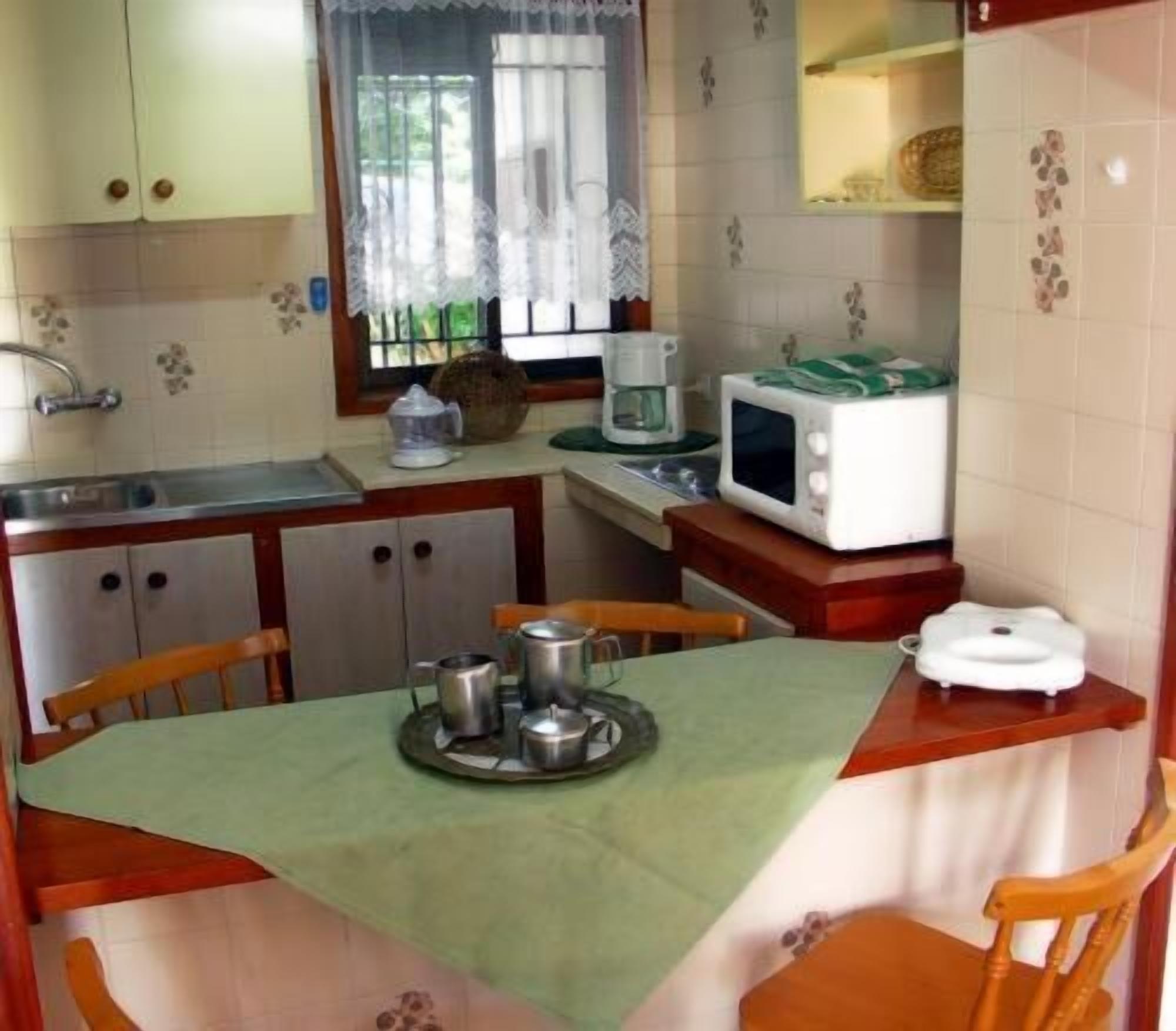 Uma cozinha compacta com mesa de jantar, cadeiras, micro-ondas, cafeteira e pia.