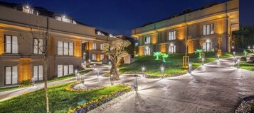 Um hotel moderno com entrada bem iluminada e jardim ajardinado.