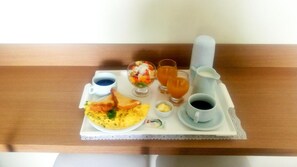 Bandeja de café da manhã com torradas, ovos mexidos, salada de frutas, café e suco.