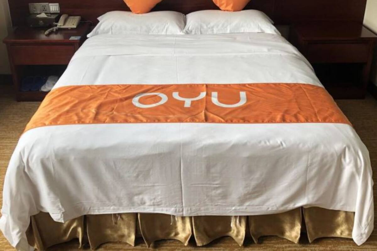 Quarto de hotel com uma cama, duas mesas de cabeceira, um telefone e um quadro na parede.