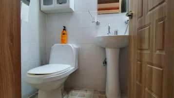 Uma casa de banho pequena com sanita, lavatório e armário.
