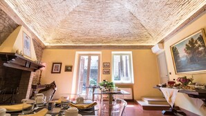 Uma área de refeições com teto de tijolos, lareira e mesa posta para uma refeição.